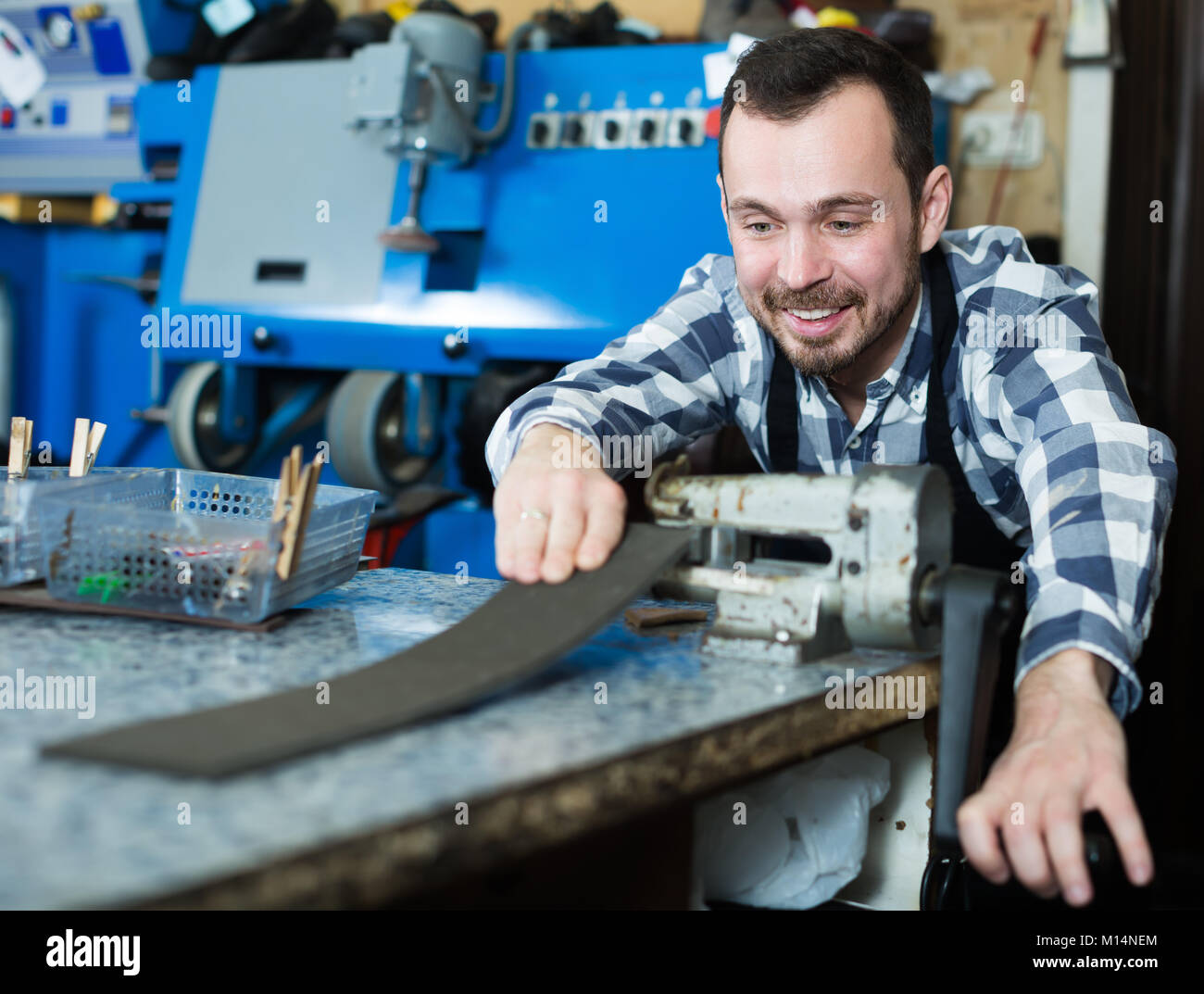 Man worker ready to use his tools for repairing in shoe repair workshop ...