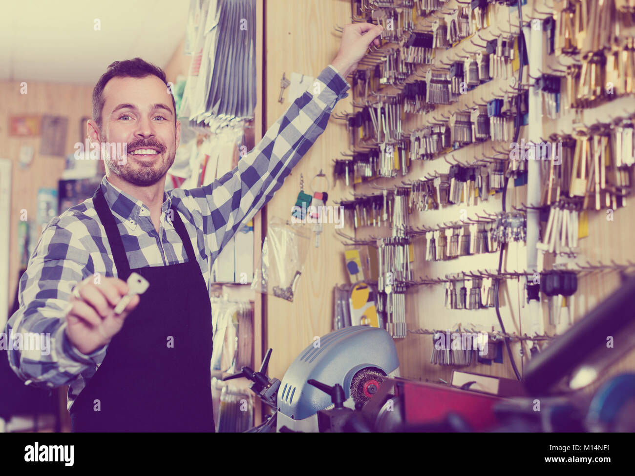 Smiling spanish male worker showing key he made in repair workshop ...