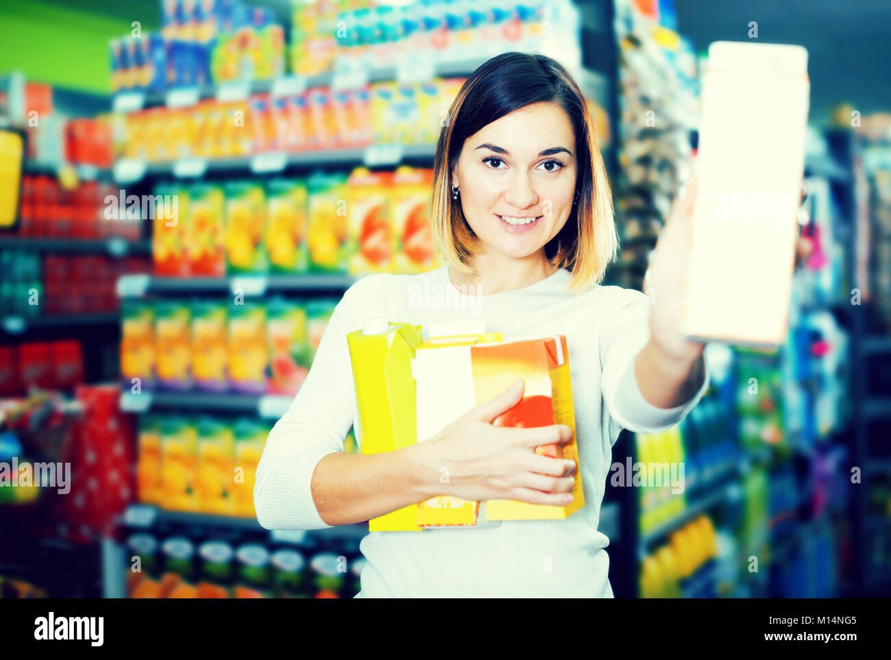 Positive young girl searching for beverages in supermarket Stock Photo ...