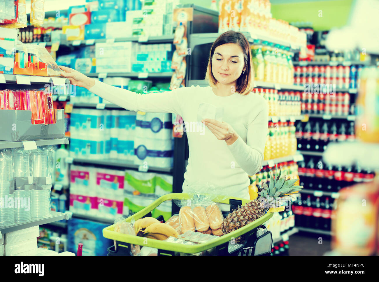 Young female shopper checking shopping list in supermarket Stock Photo ...