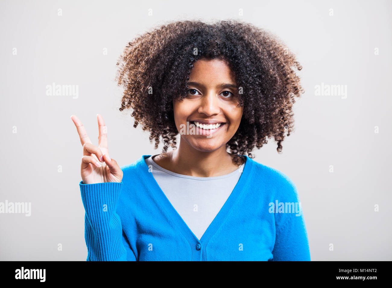 Happy woman showing victory sign Stock Photo - Alamy