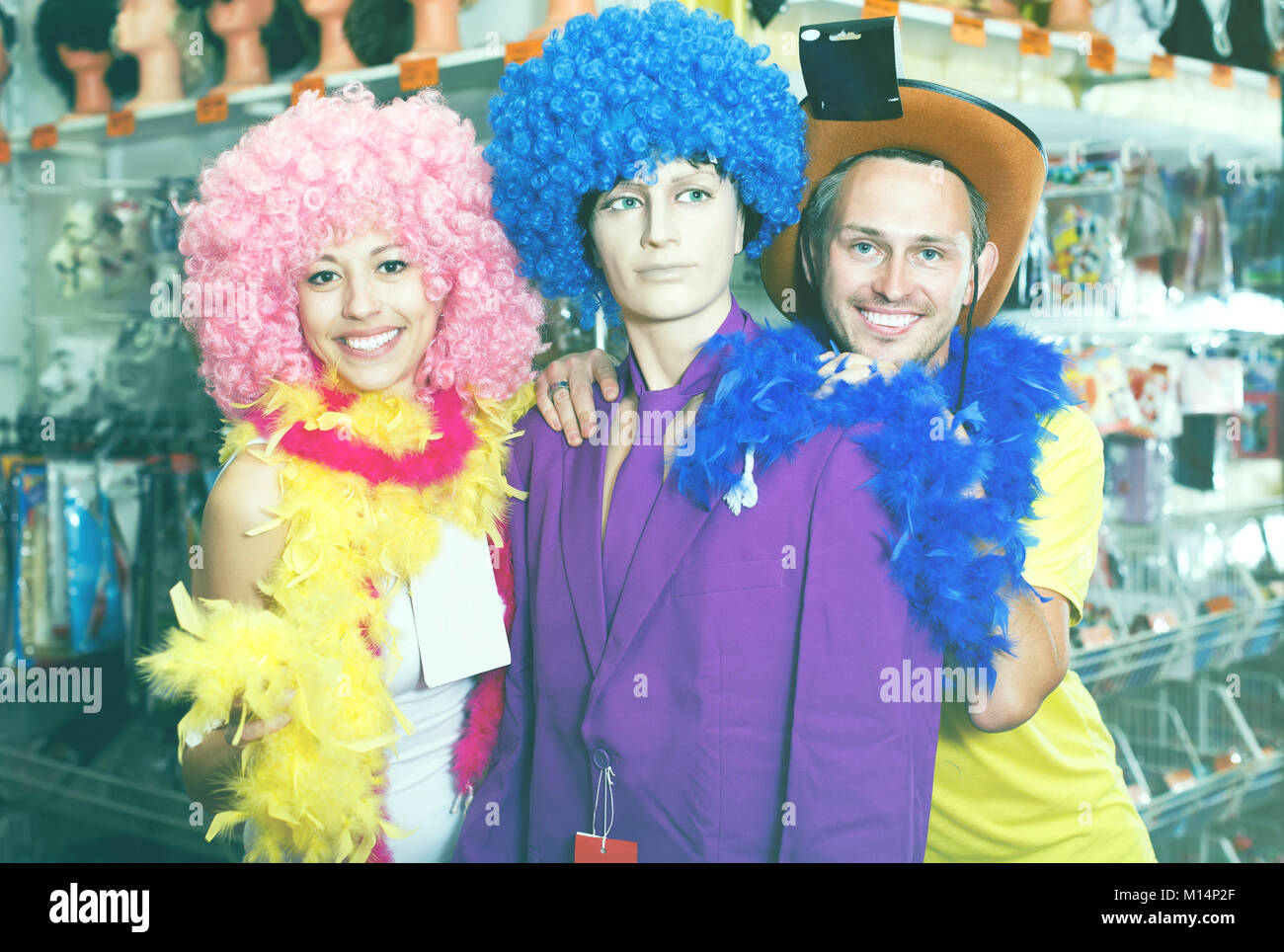 Smiling couple with mannequin dressed in blue wig and purple dress ...