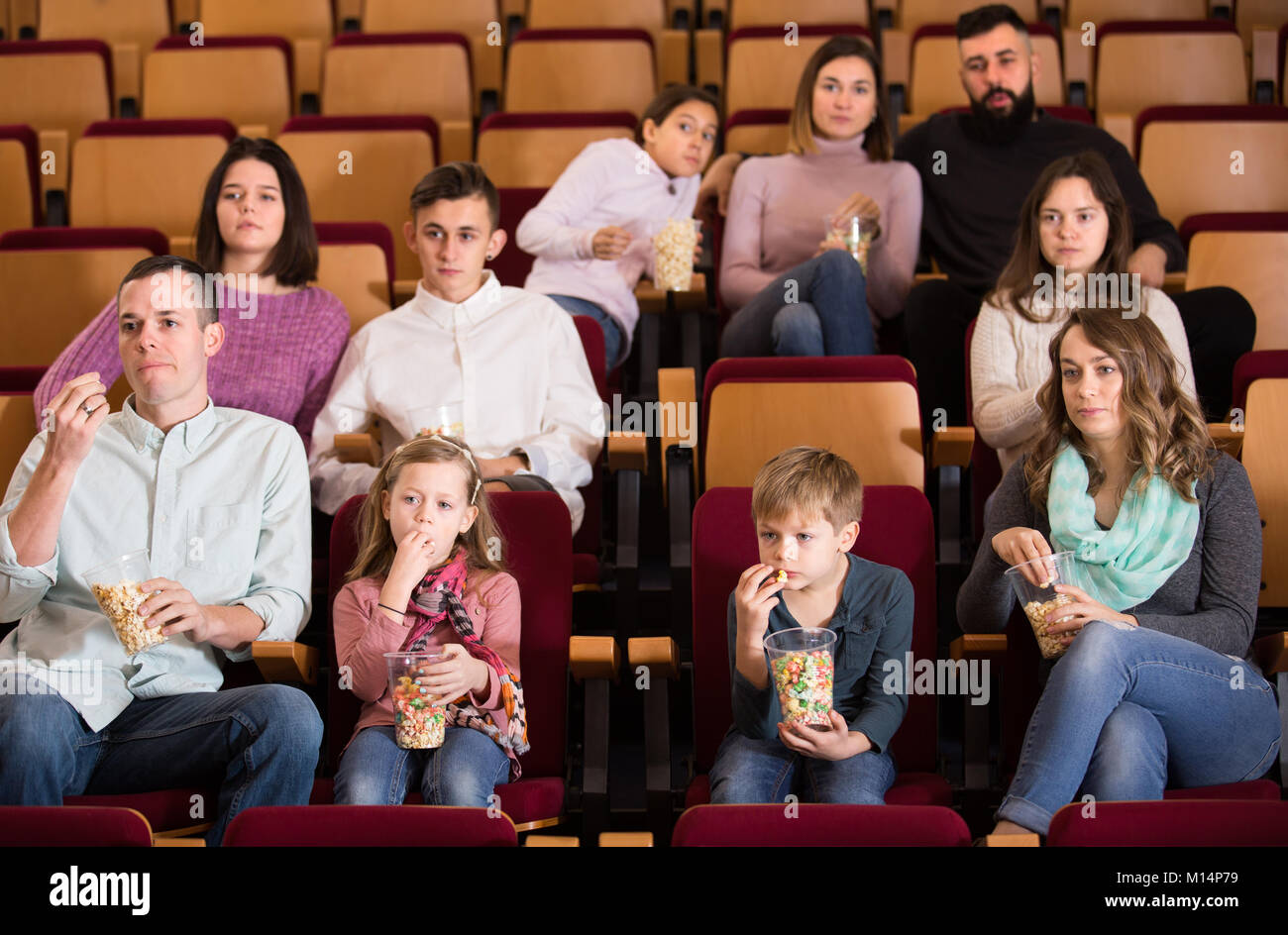 A group of people eating popcorn and watching a movie at the cinema ...