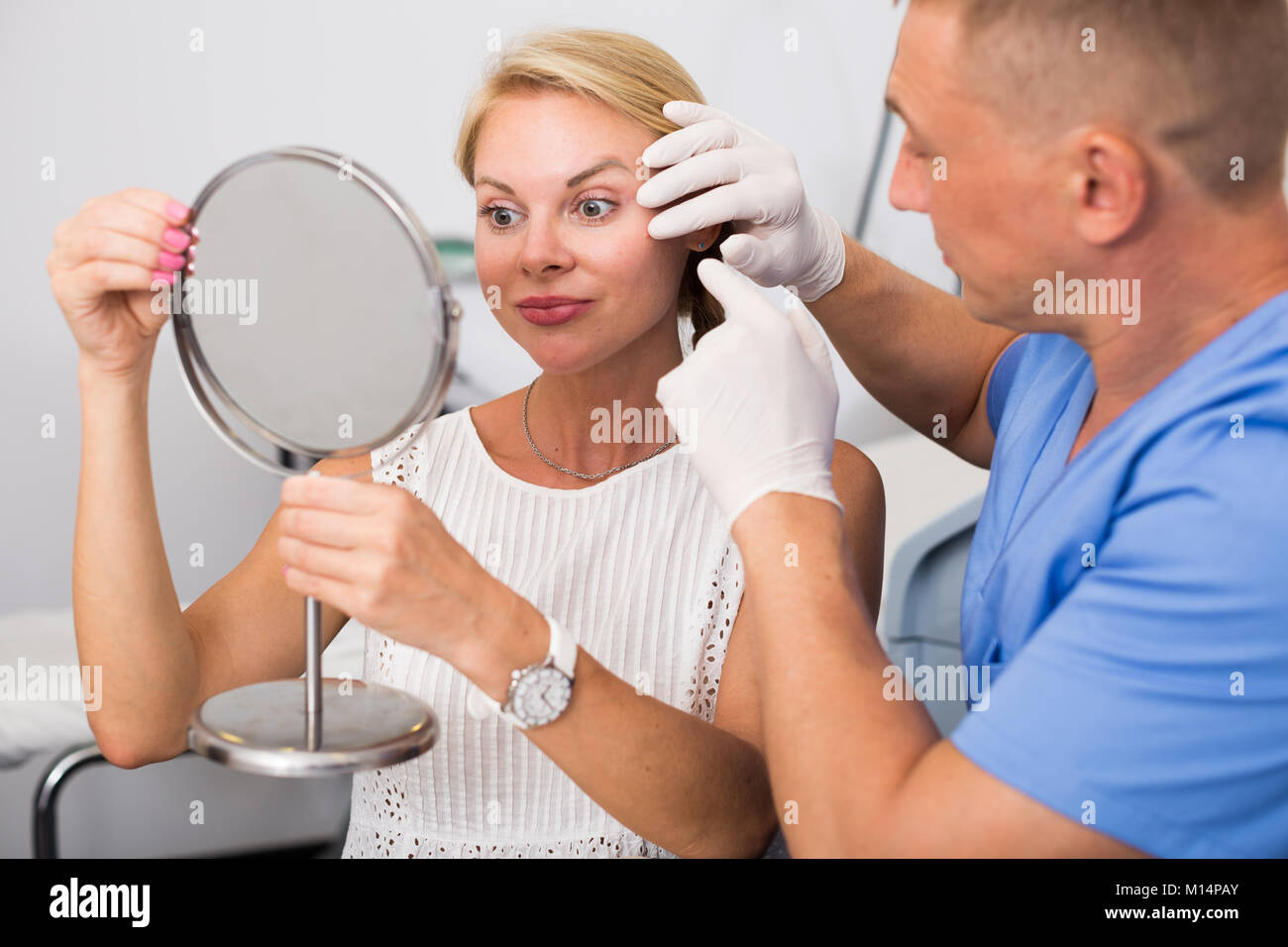 Doctor is examining woman patient behind mirror before the procedure in ...