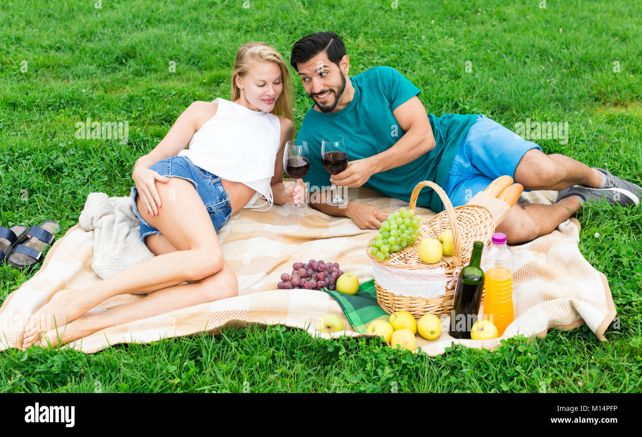 Couple are talking lying and drinking wine in time picnic outdoor Stock ...