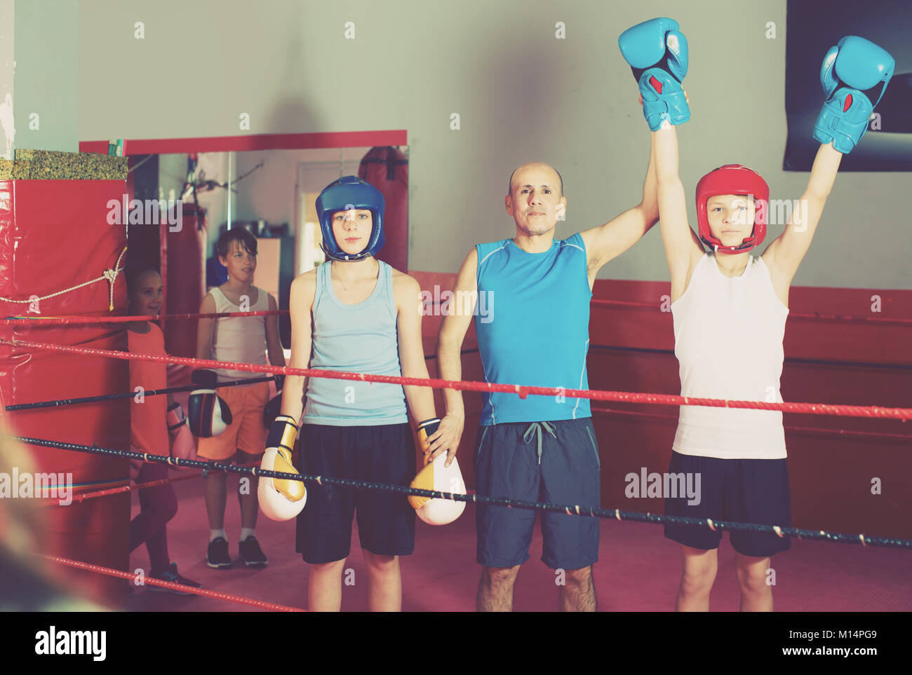Young boxing children practicing with instructor on boxing ring at gym ...