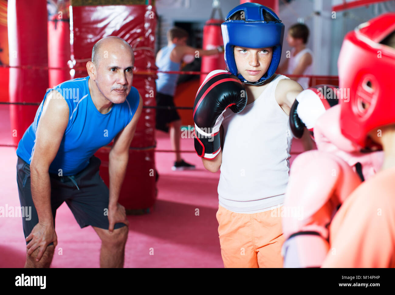 Group of children practicing with mentor on boxing ring at gym Stock ...