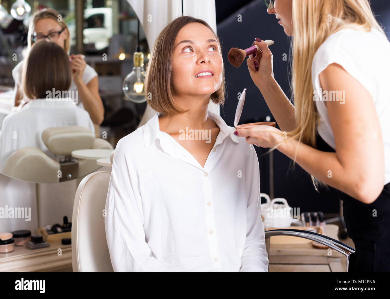 portrait of female makeup artist applying cosmetics for woman Stock ...