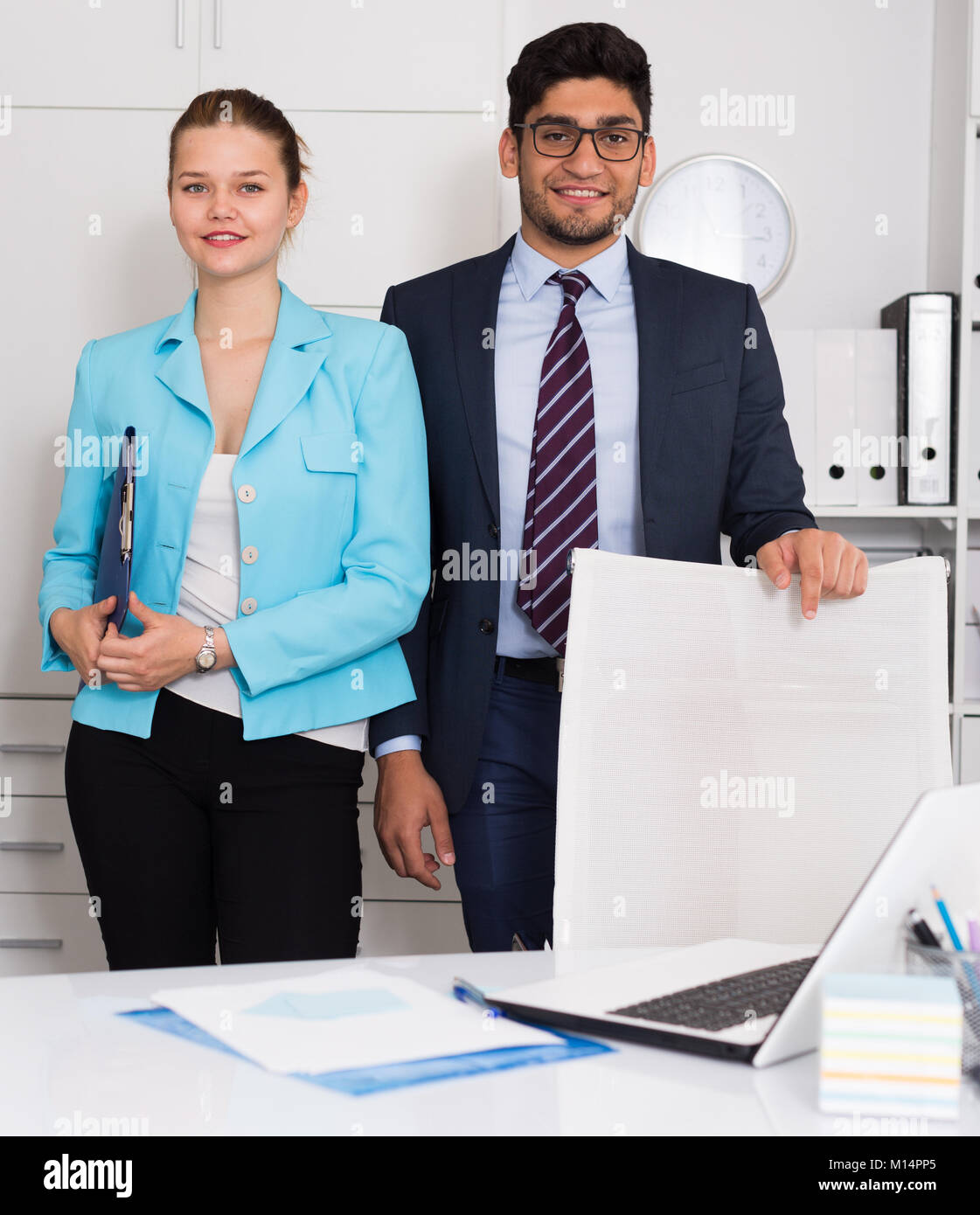 Portrait of two successful business partners standing in modern office ...
