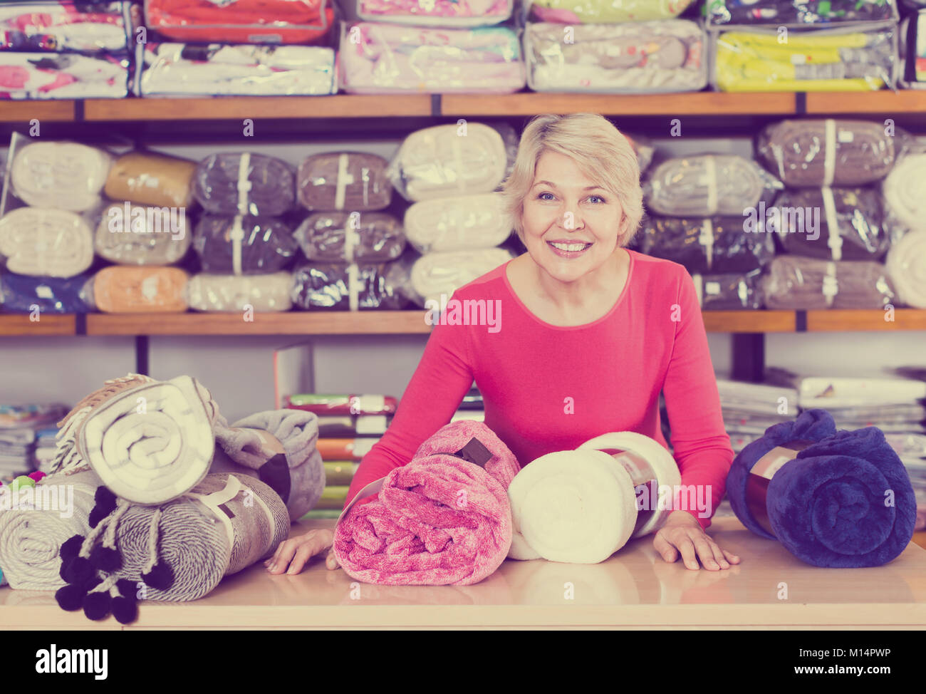Cheerful shop assistant demonstrating assortment of home textiles Stock ...