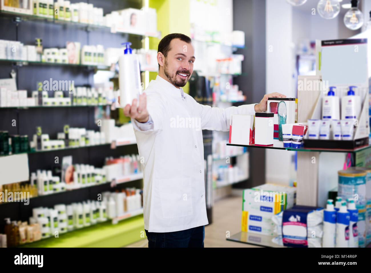 Smiling man pharmacist showing right drug in pharmacy Stock Photo - Alamy