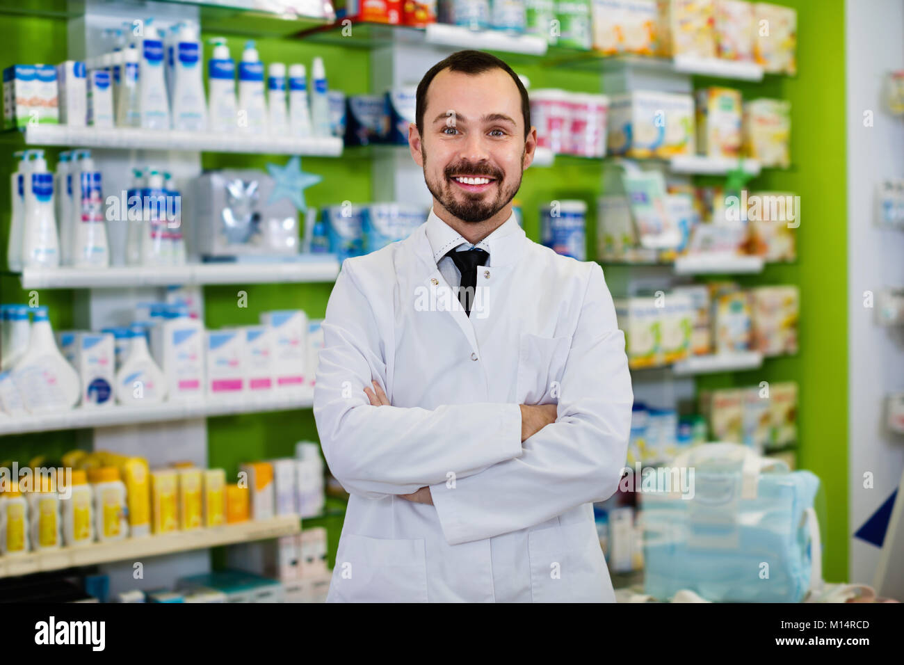 Happy cheerful positive male pharmacist demonstrating assortment of ...