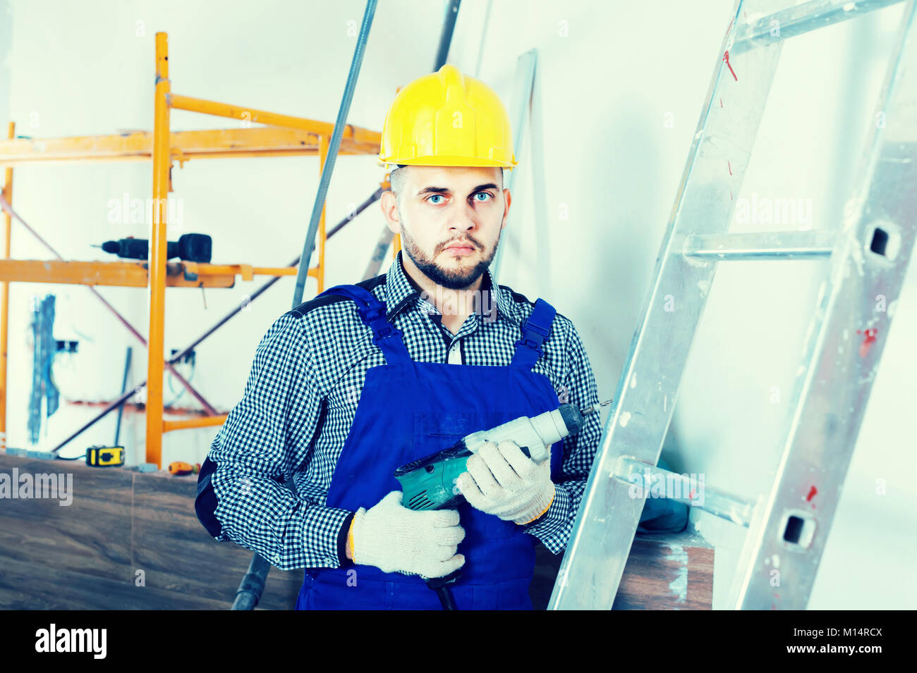 positive young british builder is ready to work with a dril at the ...