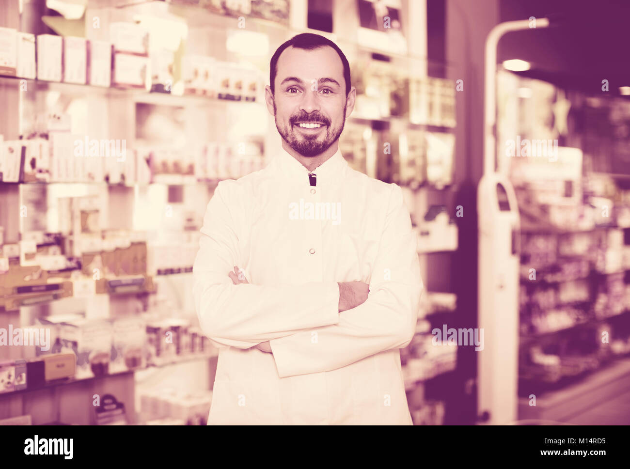 Smiling positive male pharmacist demonstrating assortment of drugs in ...