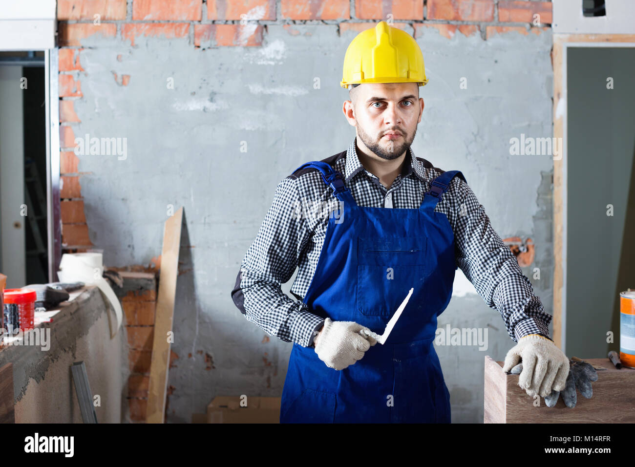 Diligent positive professional plasterer is ready to plaster the walls ...