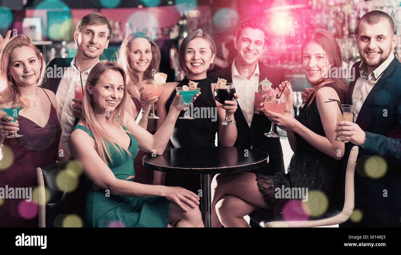 Positive colleagues dancing on corporate party with cocktails in hands ...