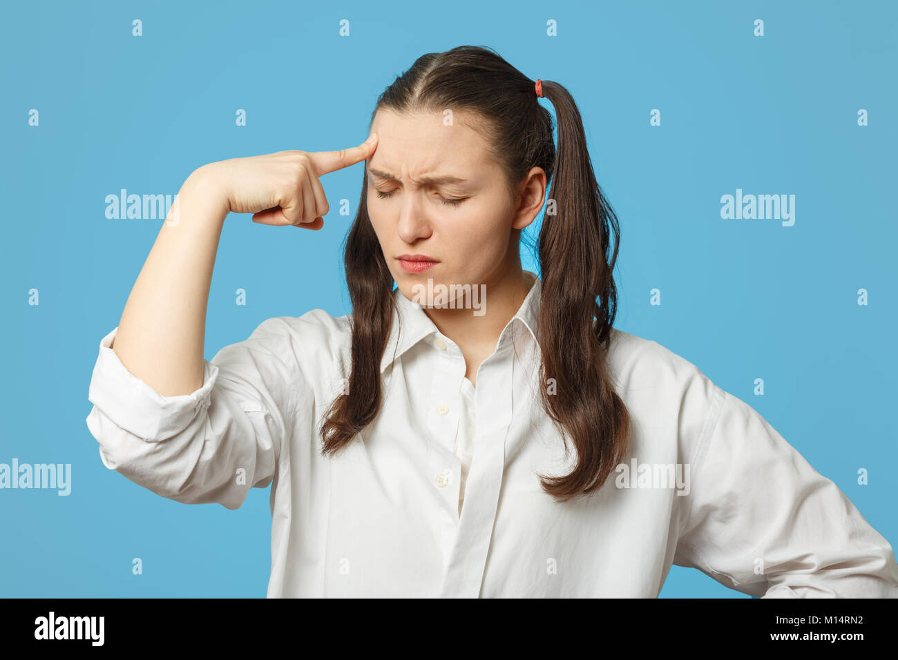 sly girl thinker on blue background with finger oh her head Stock Photo ...