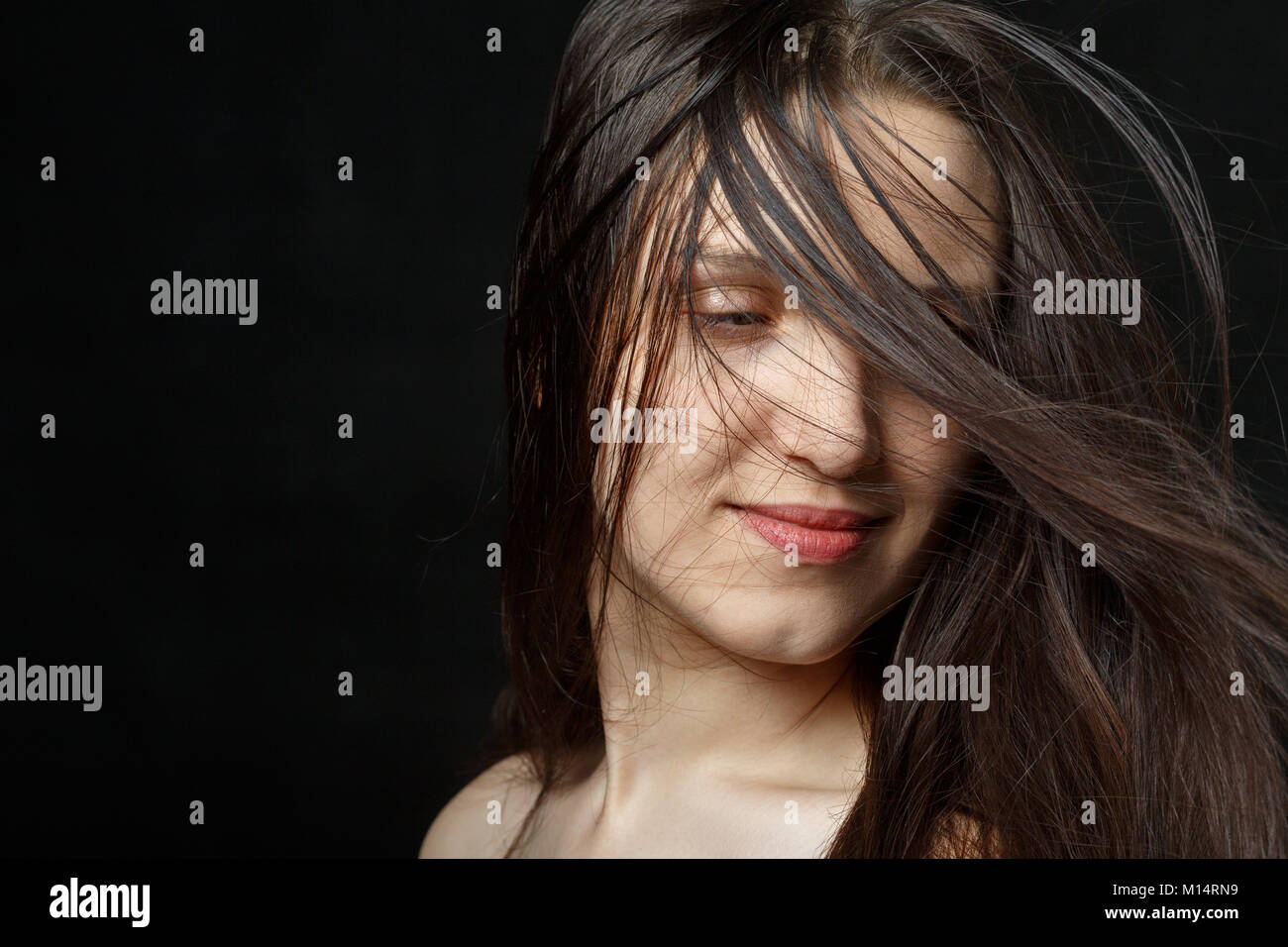 Woman With Blowing Hair On Black Background Looking Back Smiling Stock