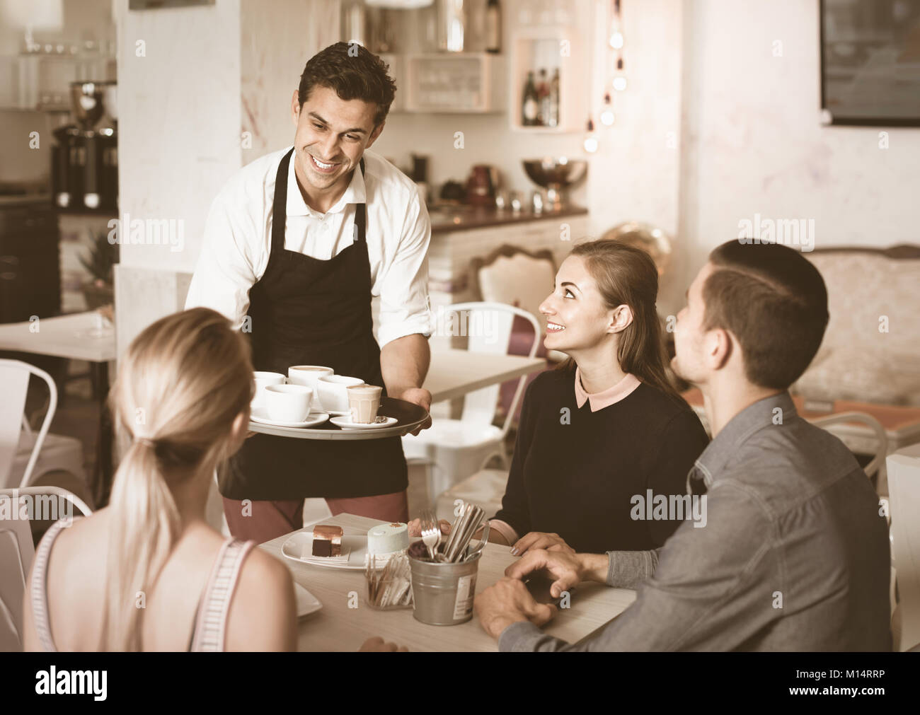Satisfied pleasant smiling waiter showing hospitality and serving ...