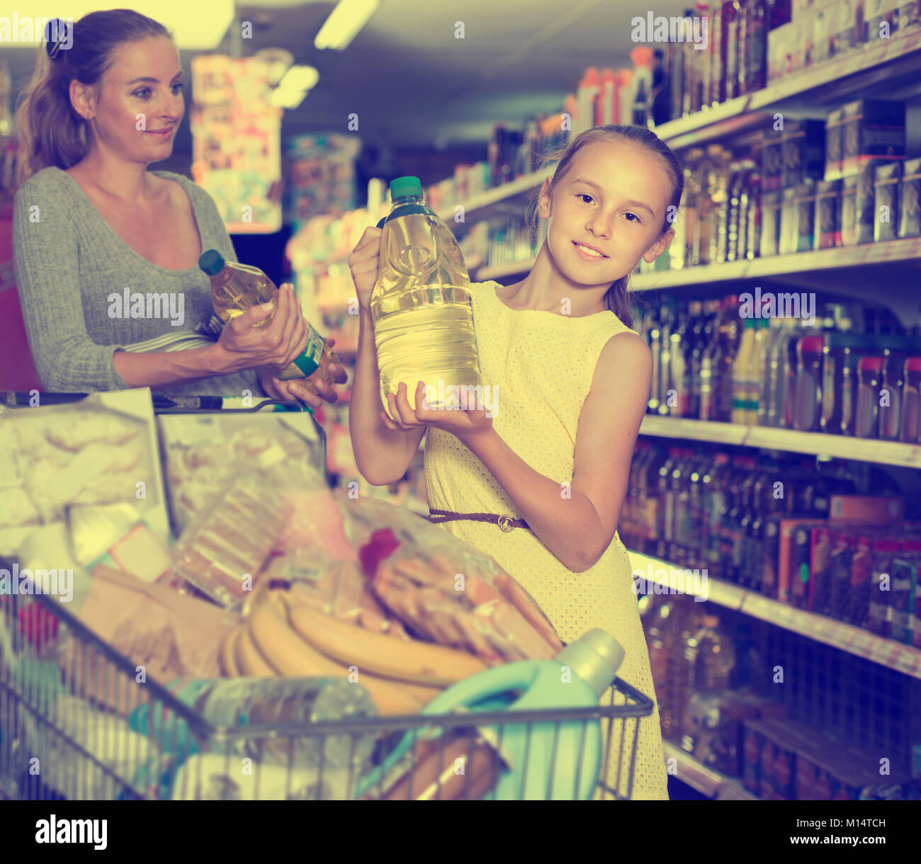 Happy girl teenager is demonstrating chosen purchases in supermarket ...