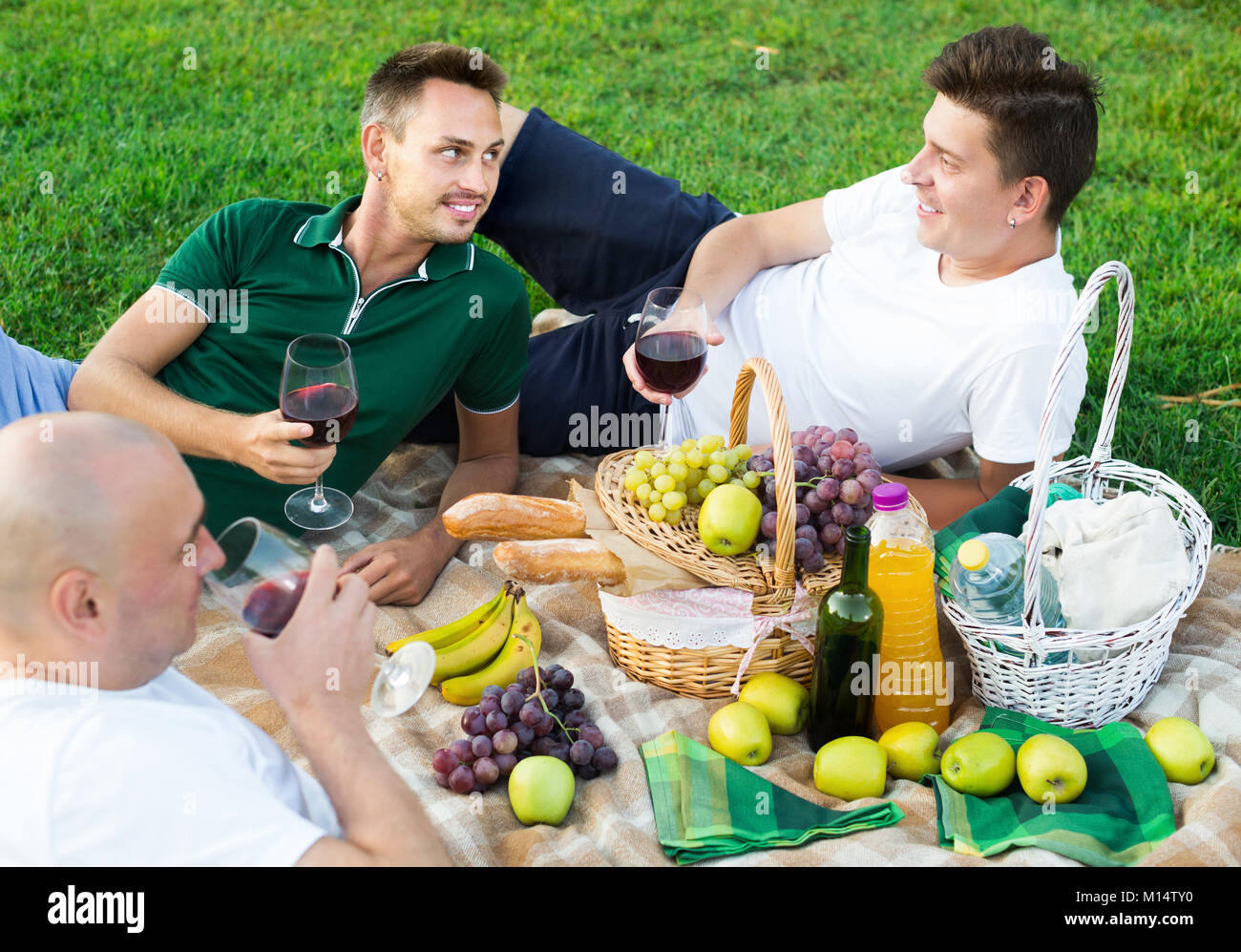 Three men friends enjoying life on picnic outdoors in male company ...