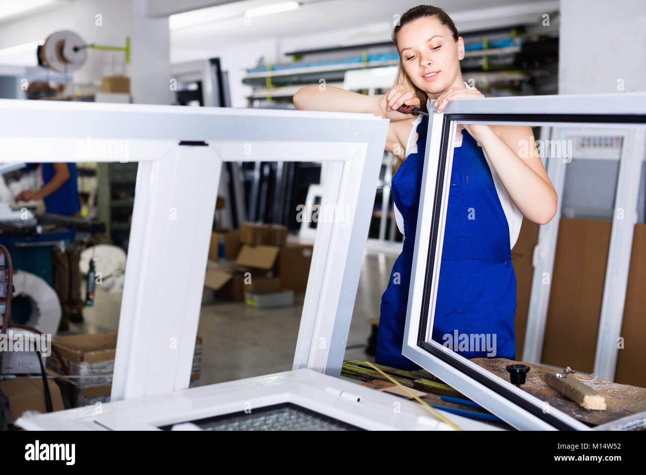 Young positive woman using screwdriver on assembling of window frame at factory Stock Photo - Alamy