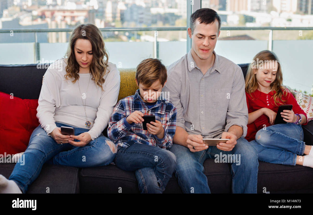 Young smiling cheerful family playing with their smartphones together ...