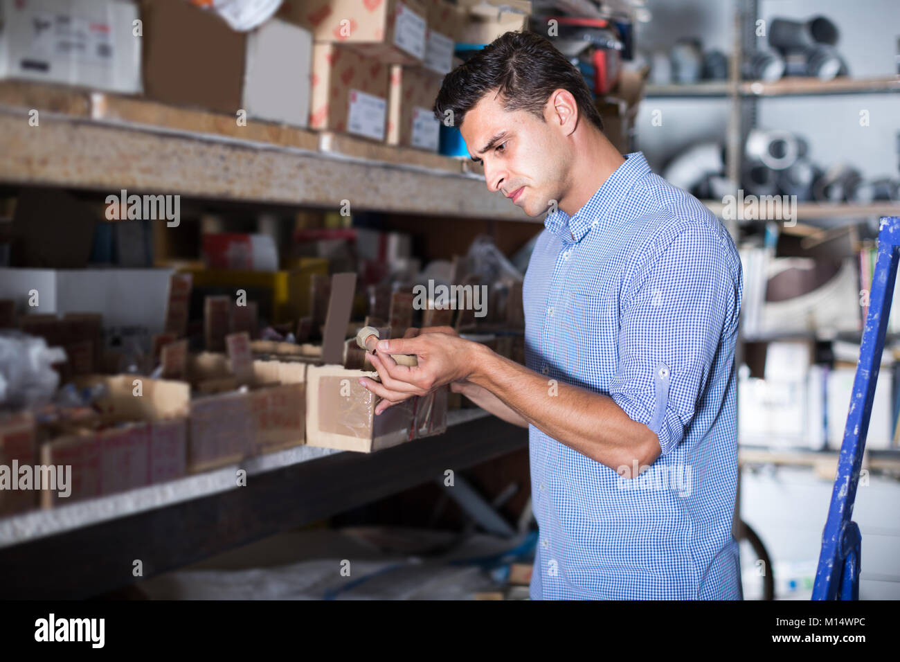 Adult male is checking small details which is in boxes near shelving in ...