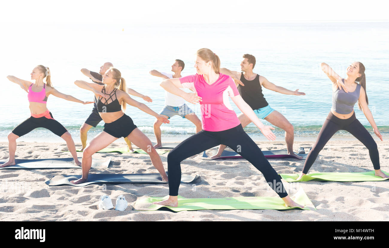 Yoga on beach, group of people practicing healthy lifestyle Stock Photo ...