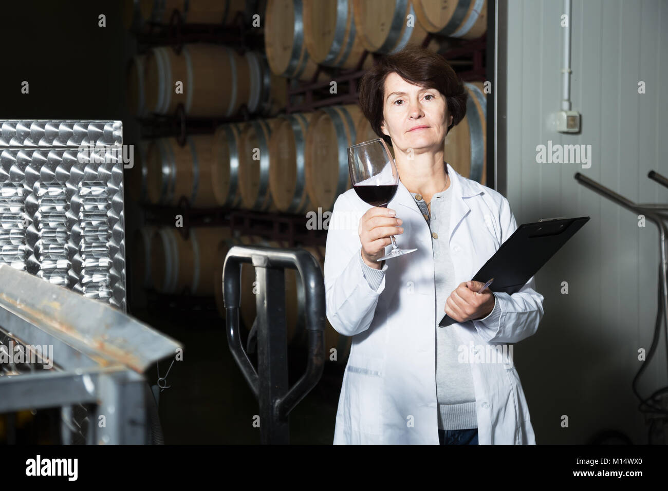 Professional sommelier woman in white uniform with glass of red wine ...