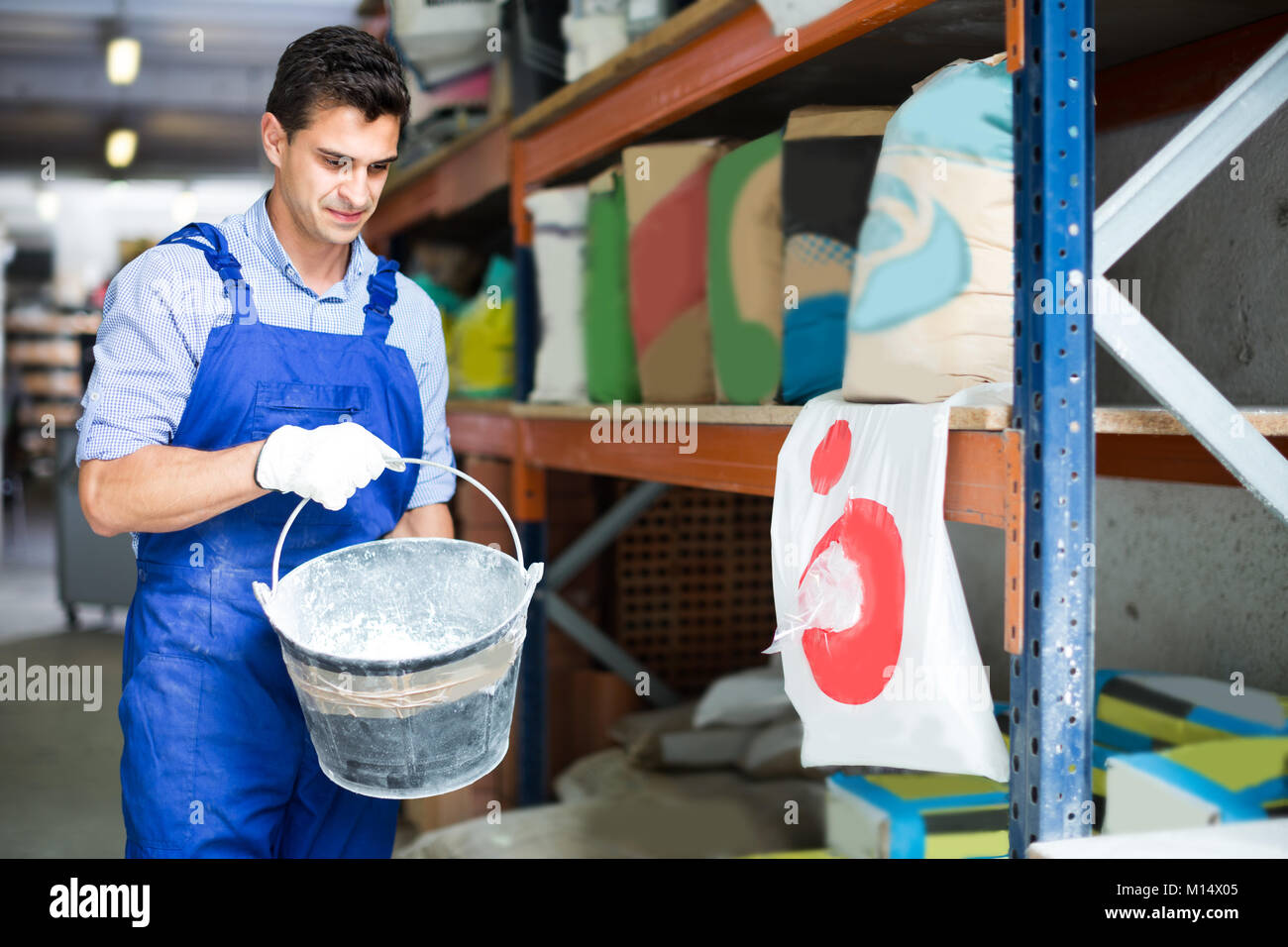 Seller is placing buckets for putty in building store Stock Photo - Alamy