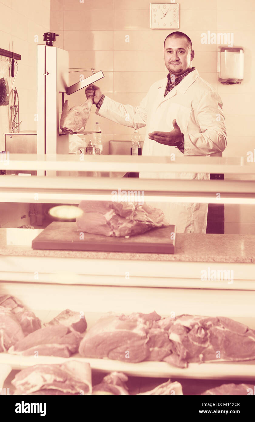 Portrait of positive male butcher in kosher section at supermarket ...