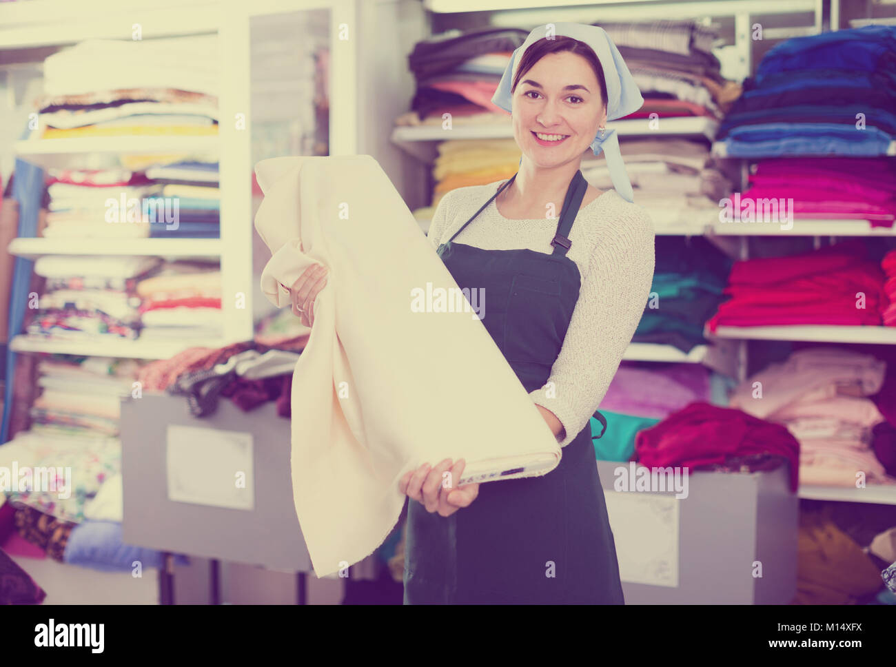 Female shop assistant demonstrating white fabric at drapery shop Stock ...