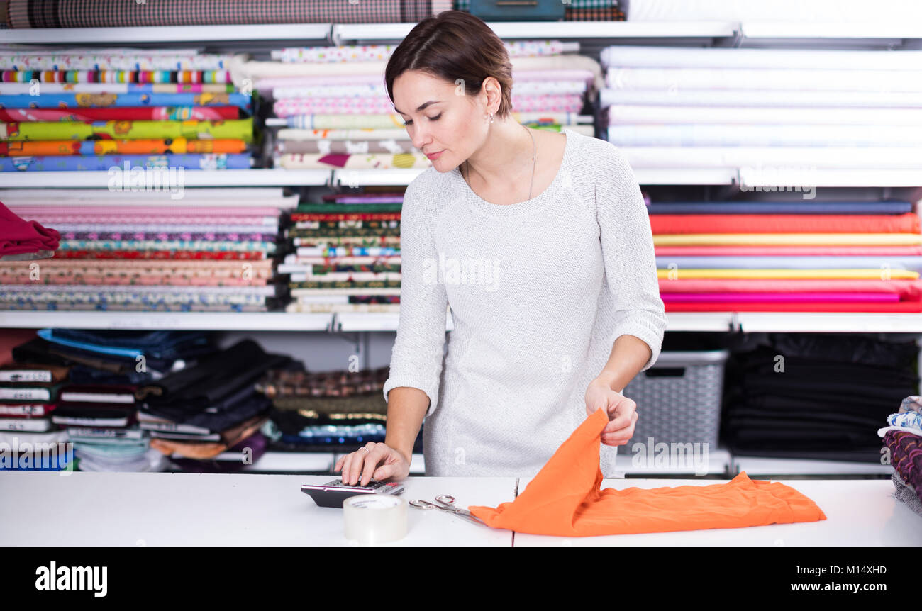 Female shop assistant measuring piece of cloth at drapery shop Stock ...