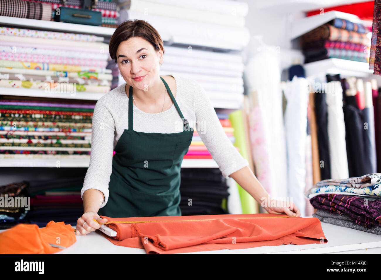 Female shop assistant measuring piece of cloth at drapery shop Stock ...