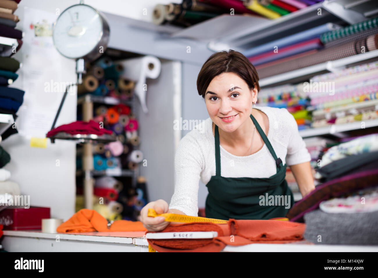Female shop assistant measuring piece of cloth at drapery shop Stock ...