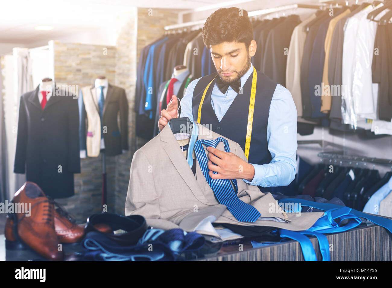 Young male designer is creating business image in men's clothes store ...