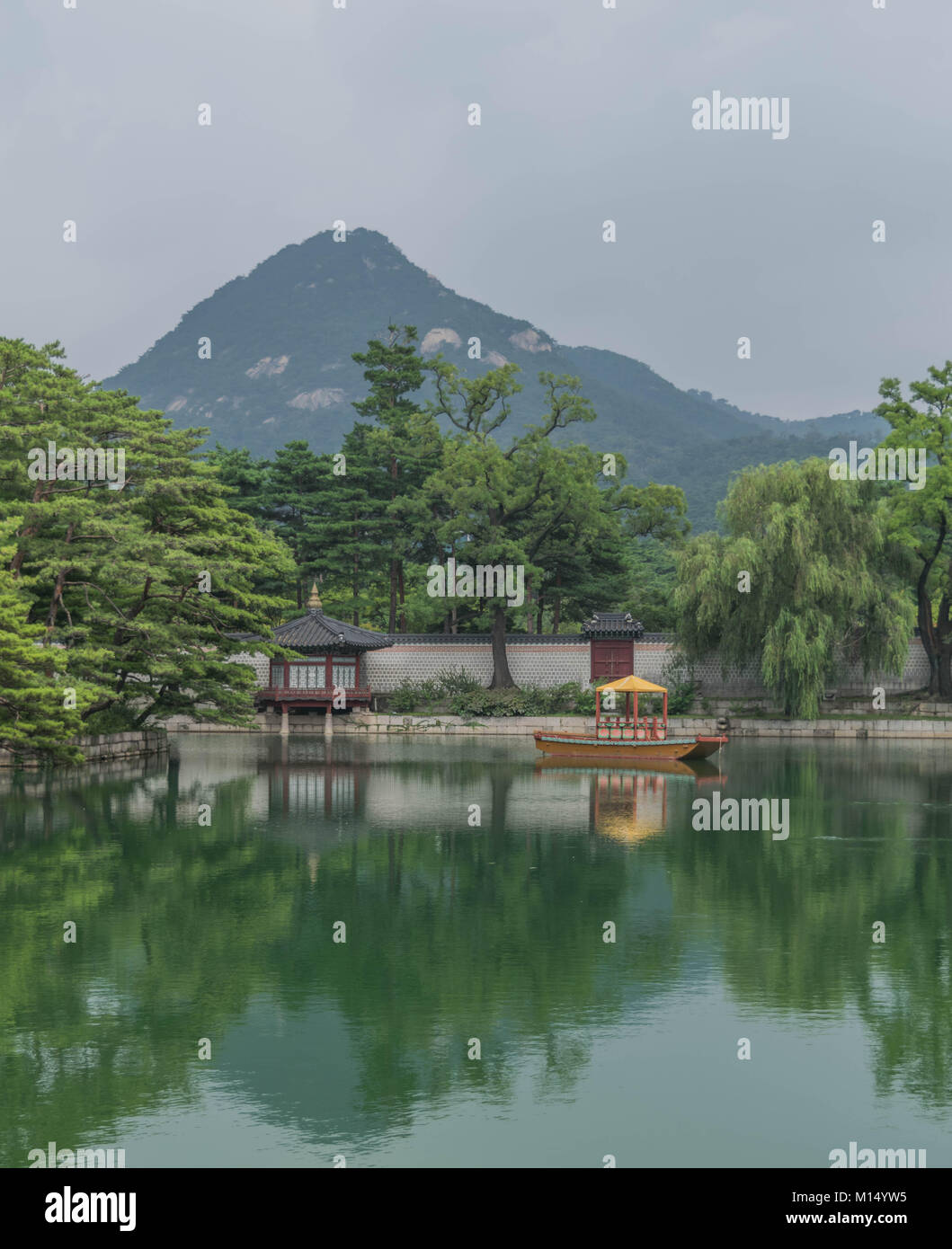 A small man-made lake with a small colorful boat, beautiful trees, and ...