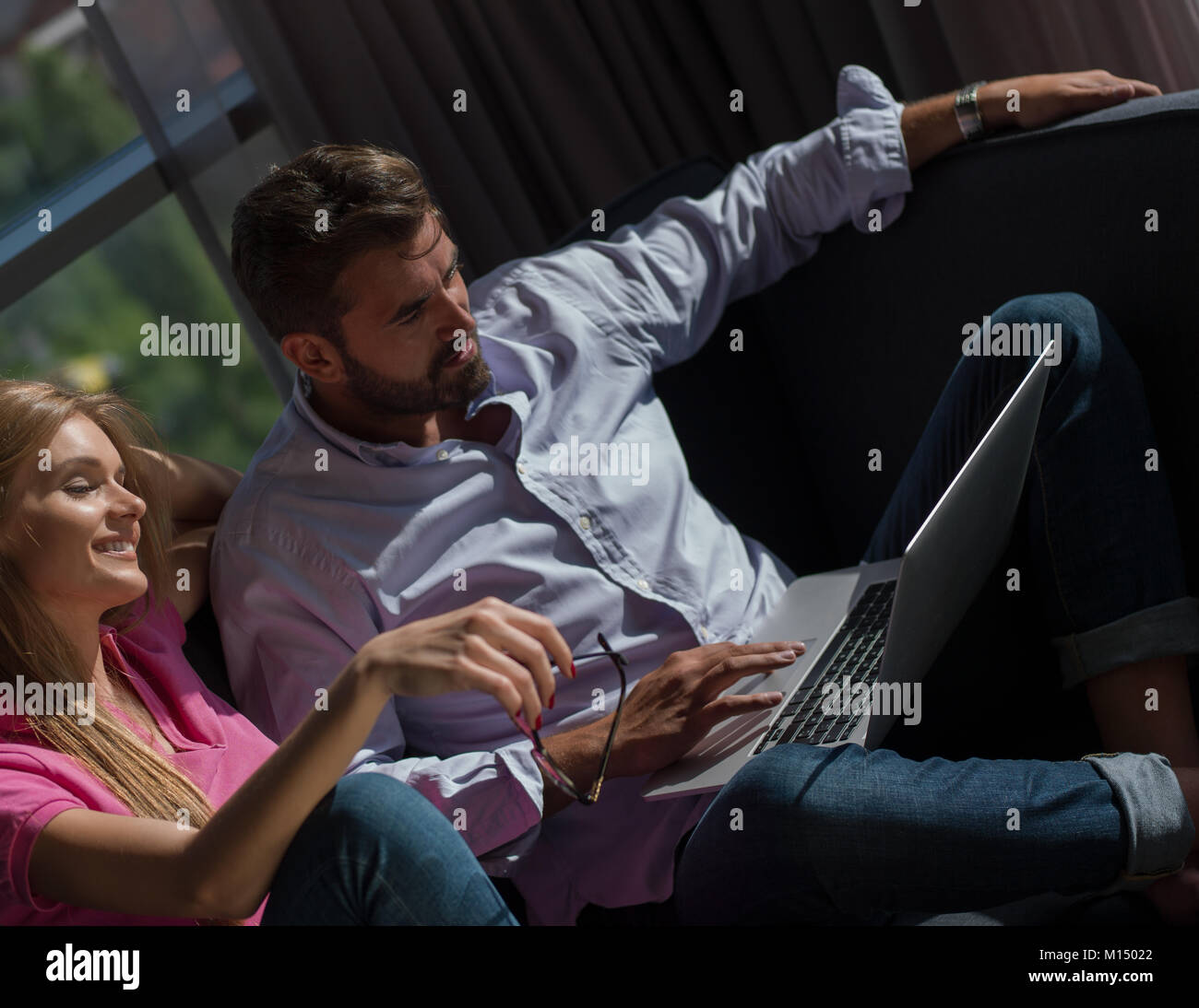 Young couple relaxing at luxury home using laptop computer reading in ...