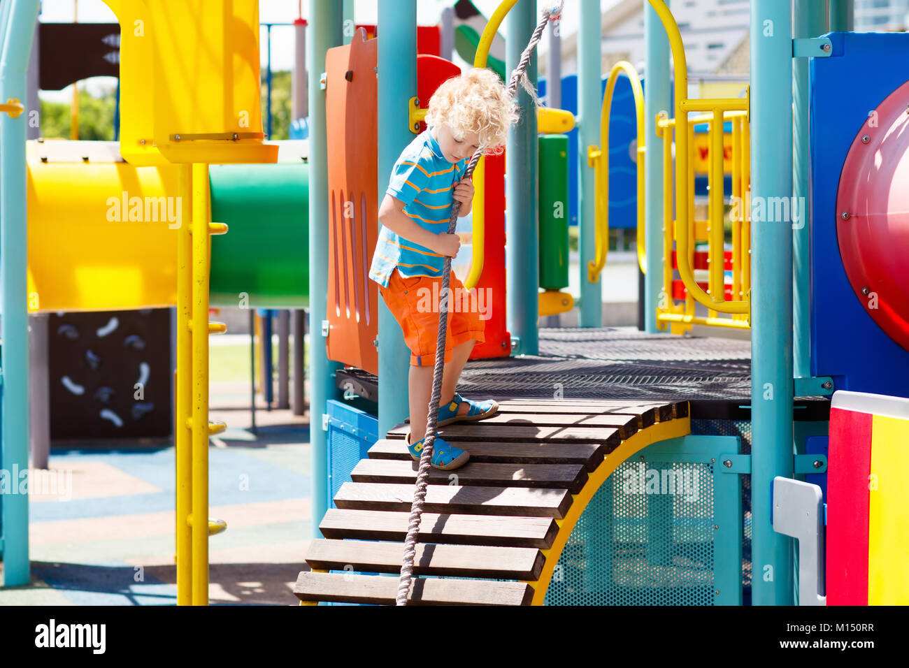 Kids climbing and sliding on outdoor playground. Children play in sunny ...