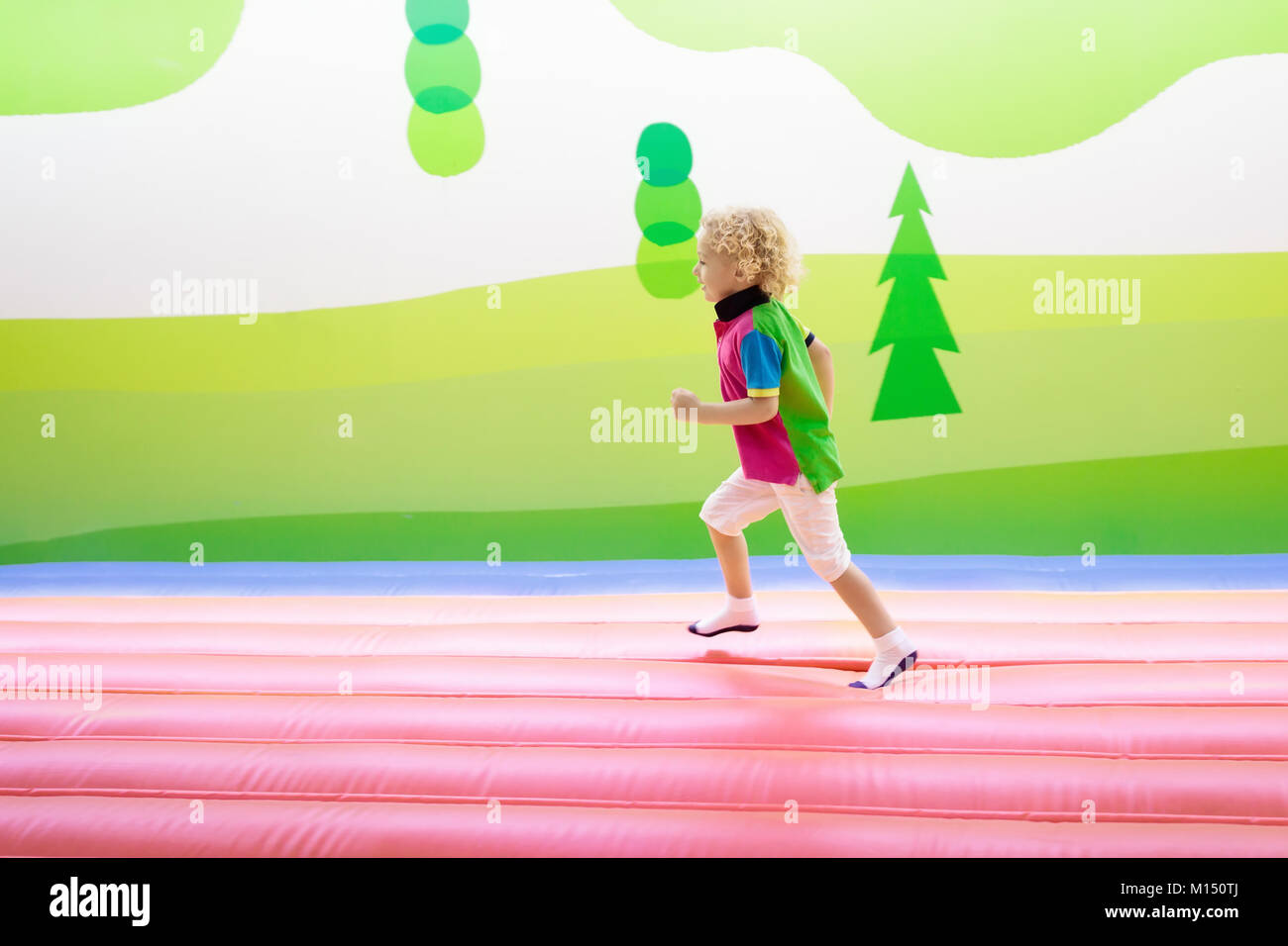 Child jumping on colorful playground trampoline. Kids jump in ...