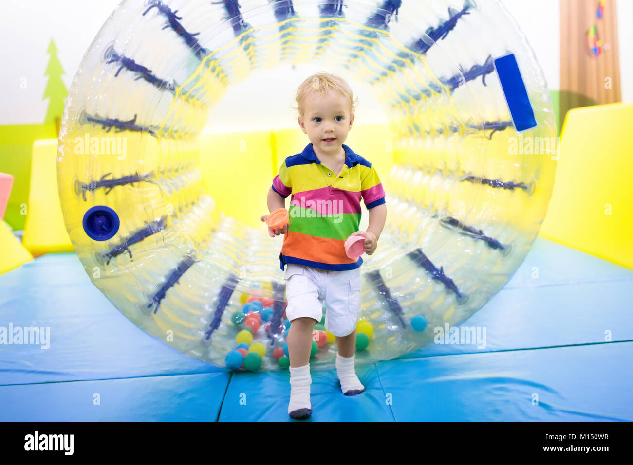 Child in roller wheel jumping on colorful playground trampoline. Kids ...
