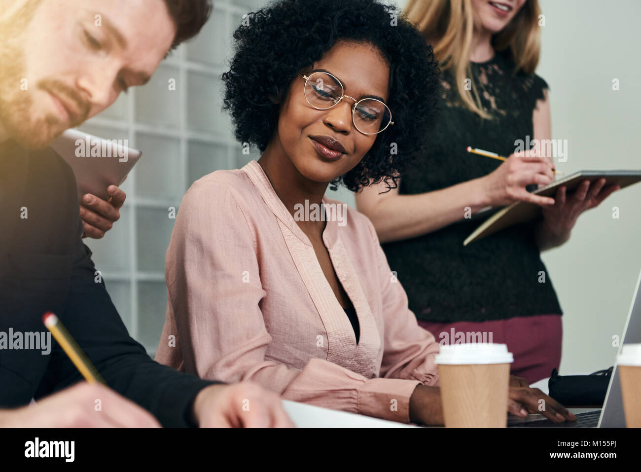 African businesswoman watching a business colleague work while sitting ...