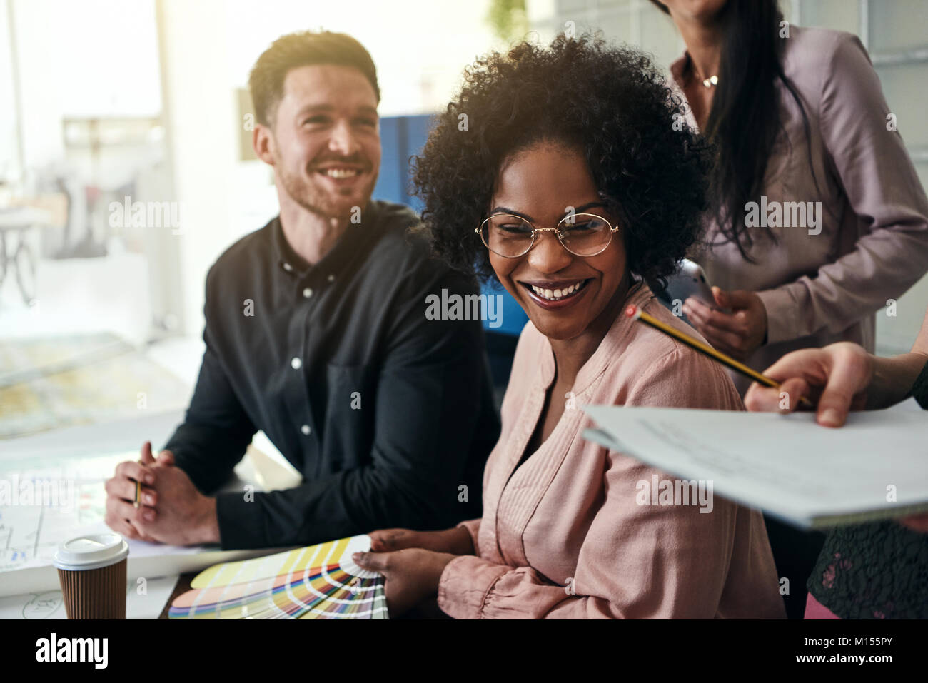 Diverse group of smiling business colleagues laughing while working ...