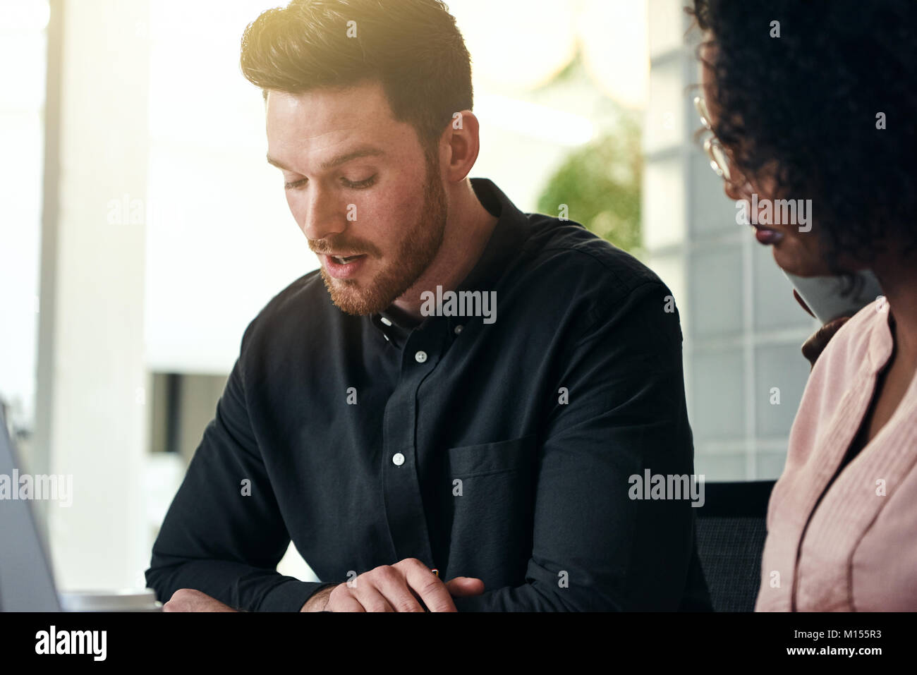 Two focused young work collegues talking business together while ...