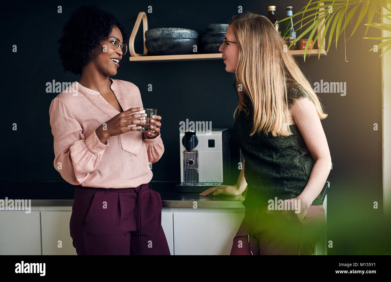 Two diverse female work colleagues smiling and talking together while ...