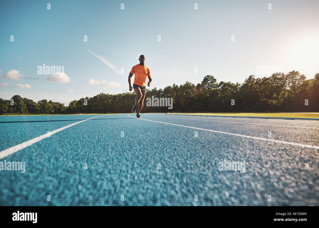 Focused young African male athlete in sportswear racing alone along a ...