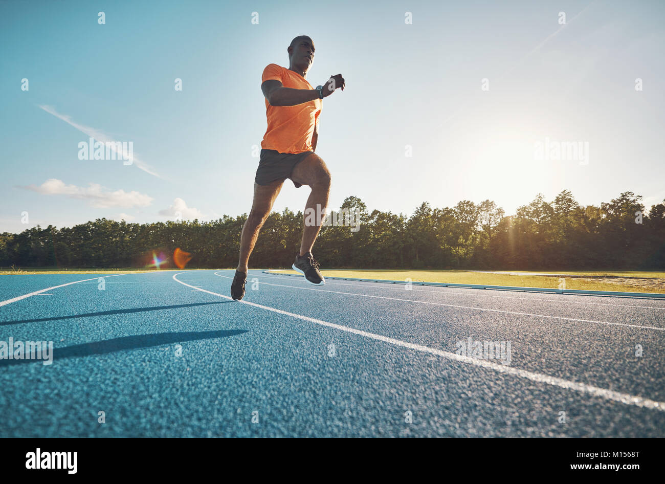 Fit young African male athlete in sportswear racing alone down a ...