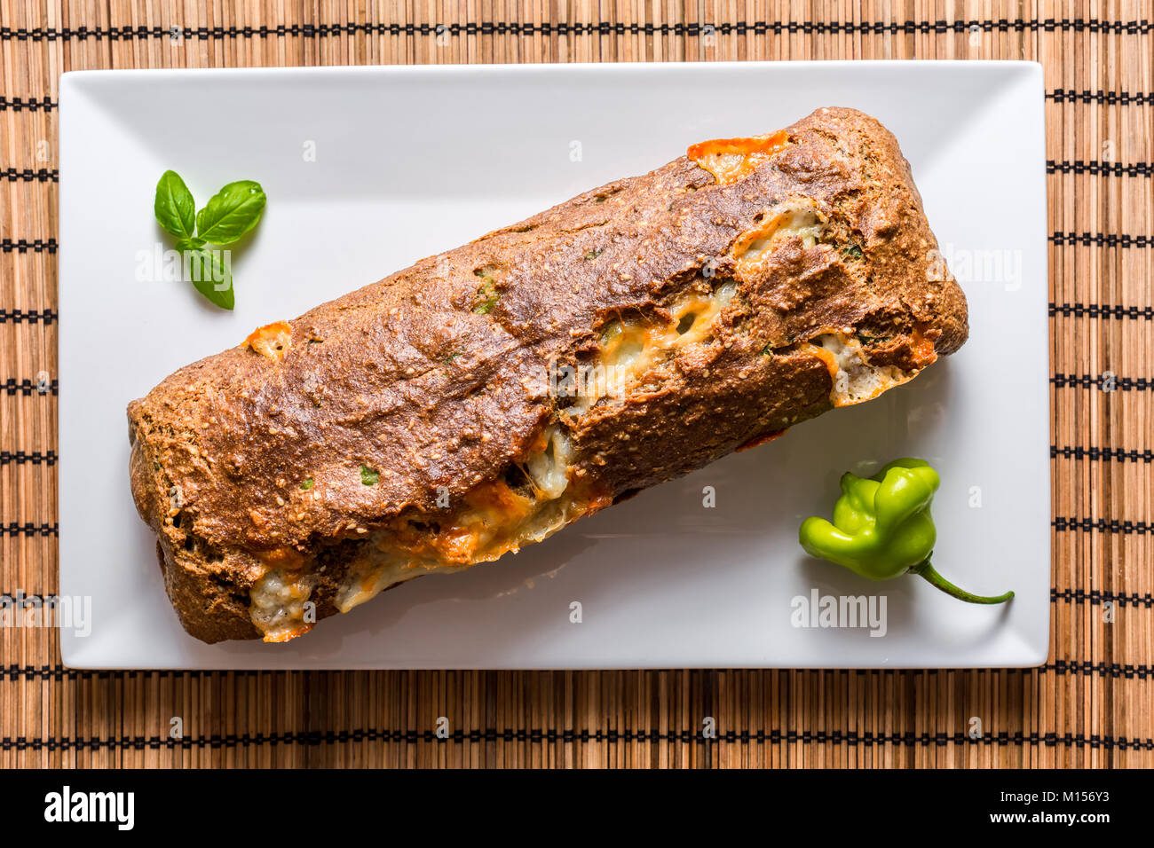 Delicious brown bread with cheese on white rectangular plate from above ...