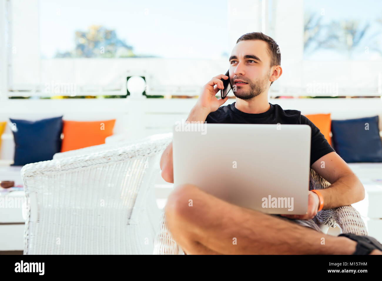 Handsome man on deck with mobile phone and laptop on summer resort ...